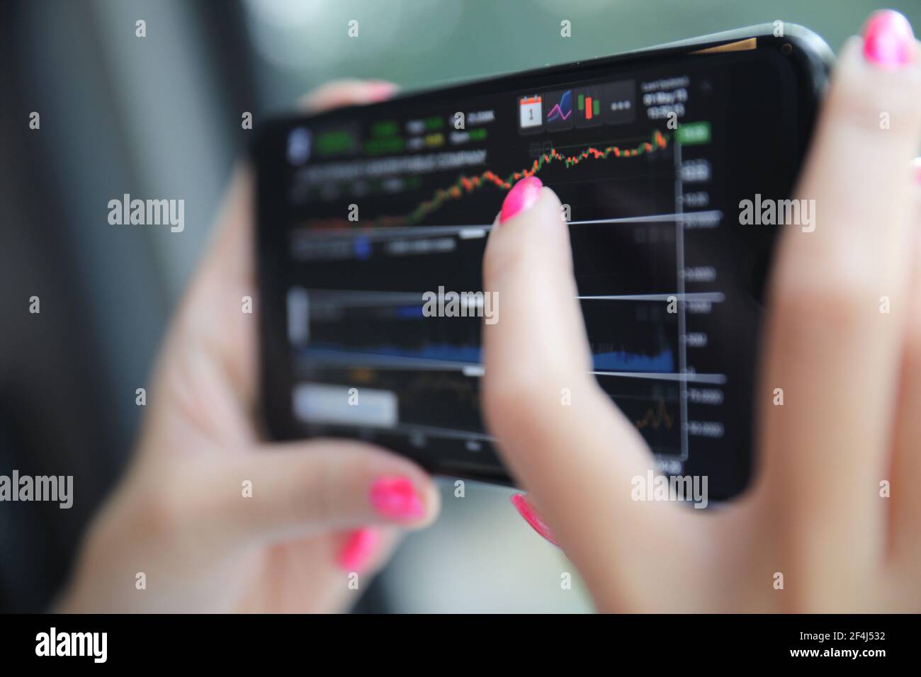Female hand with smartphone trading stock online in coffee shop ...