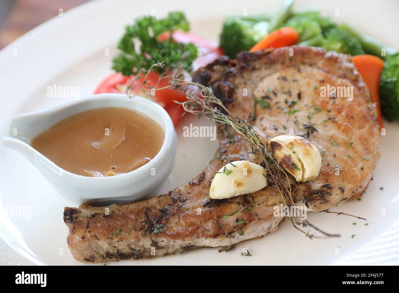 grilled pork chop with vegetable on dish with wood table background ...