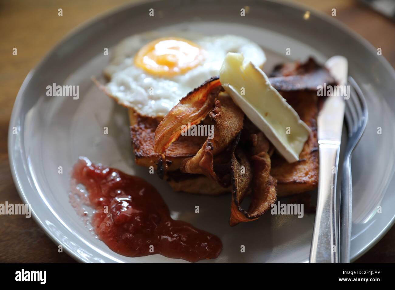Breakfast french toast with bacon egg and cheese with jam on wood table ...