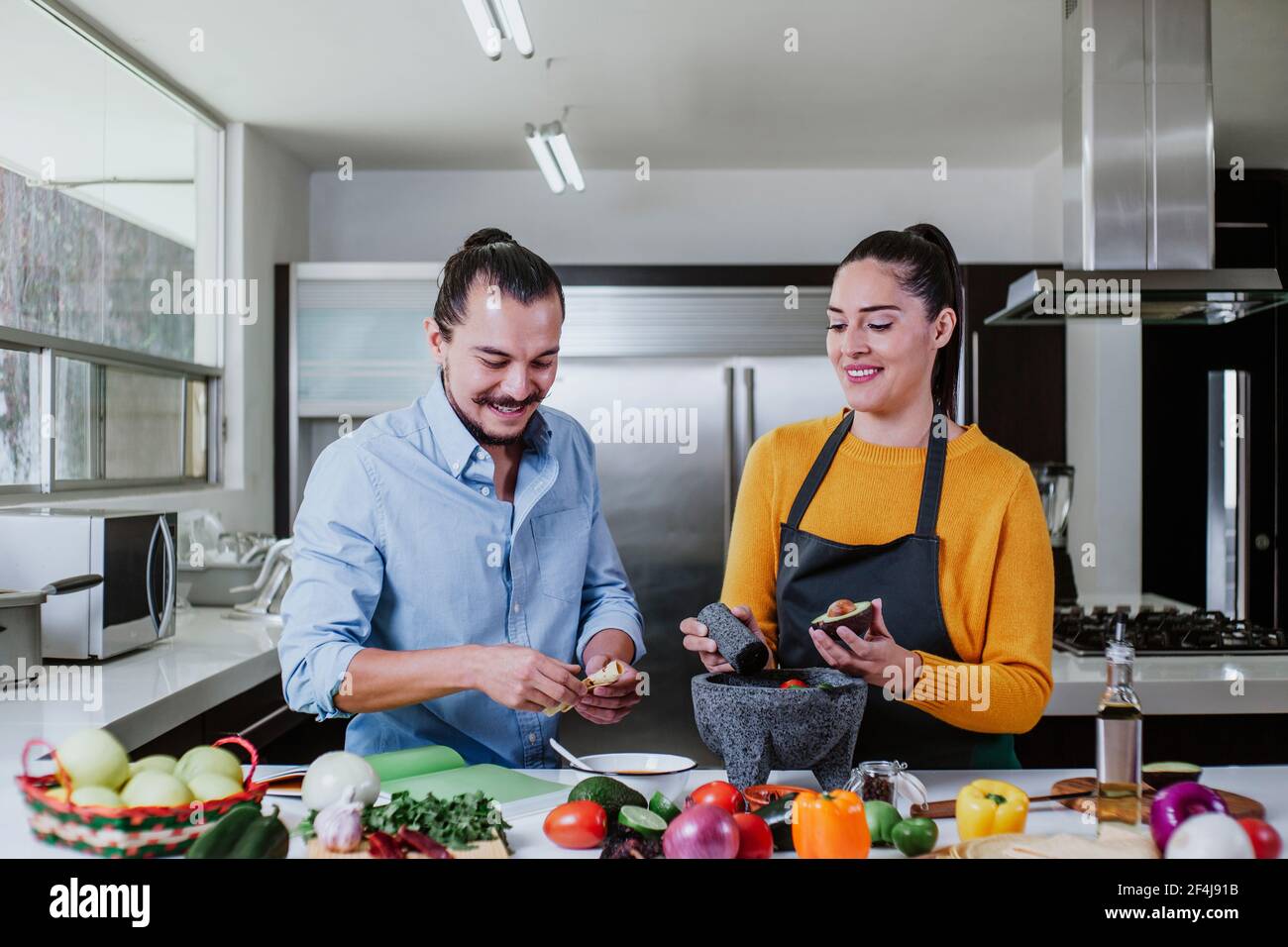 latin couple cooking mexican sauce together in their kitchen at home in ...