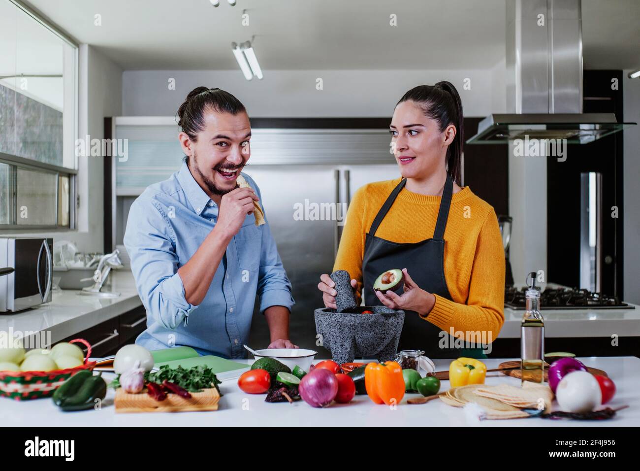 latin couple cooking mexican sauce together in their kitchen at home in ...