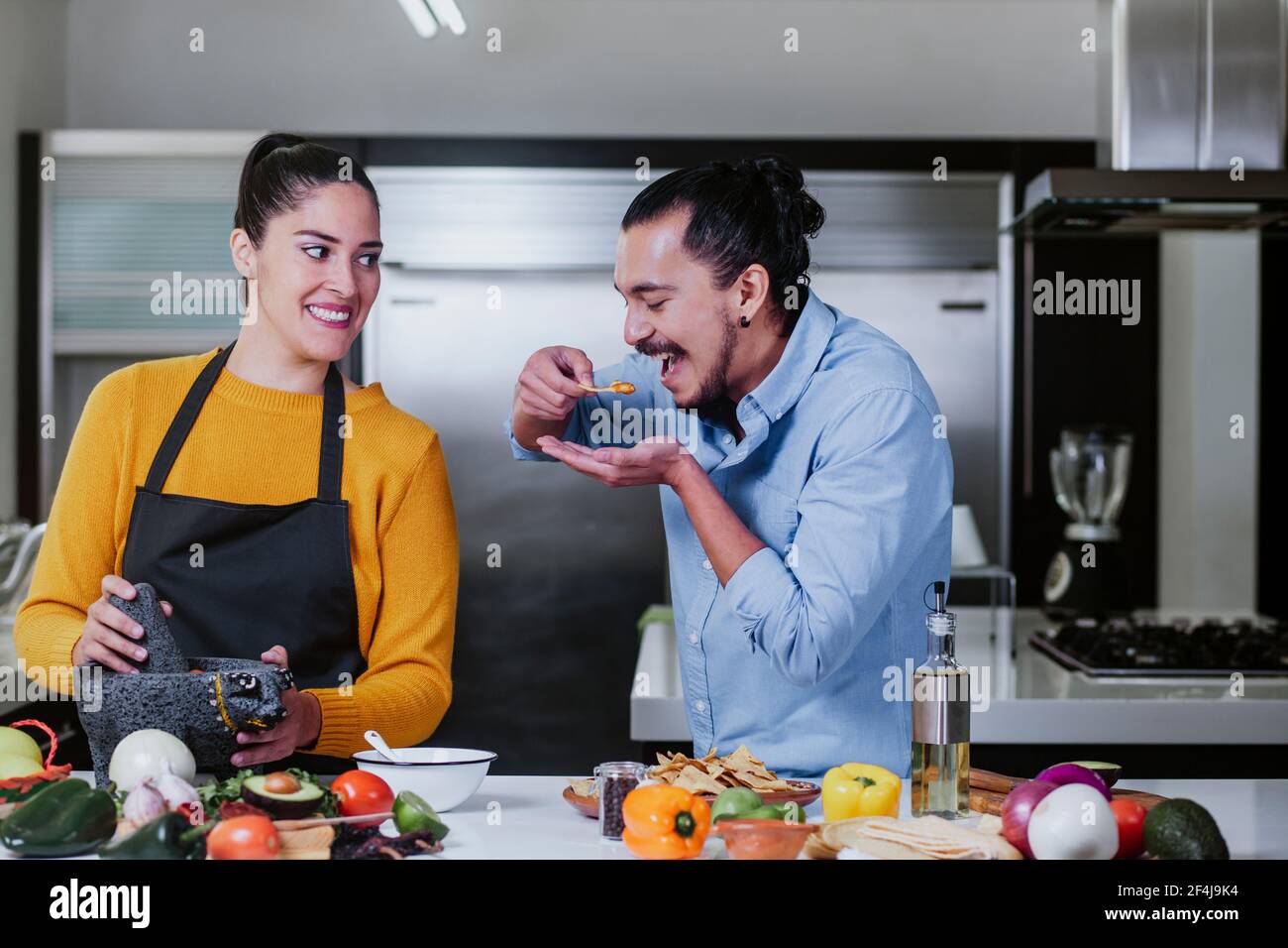 latin couple cooking mexican sauce together in their kitchen at home in ...