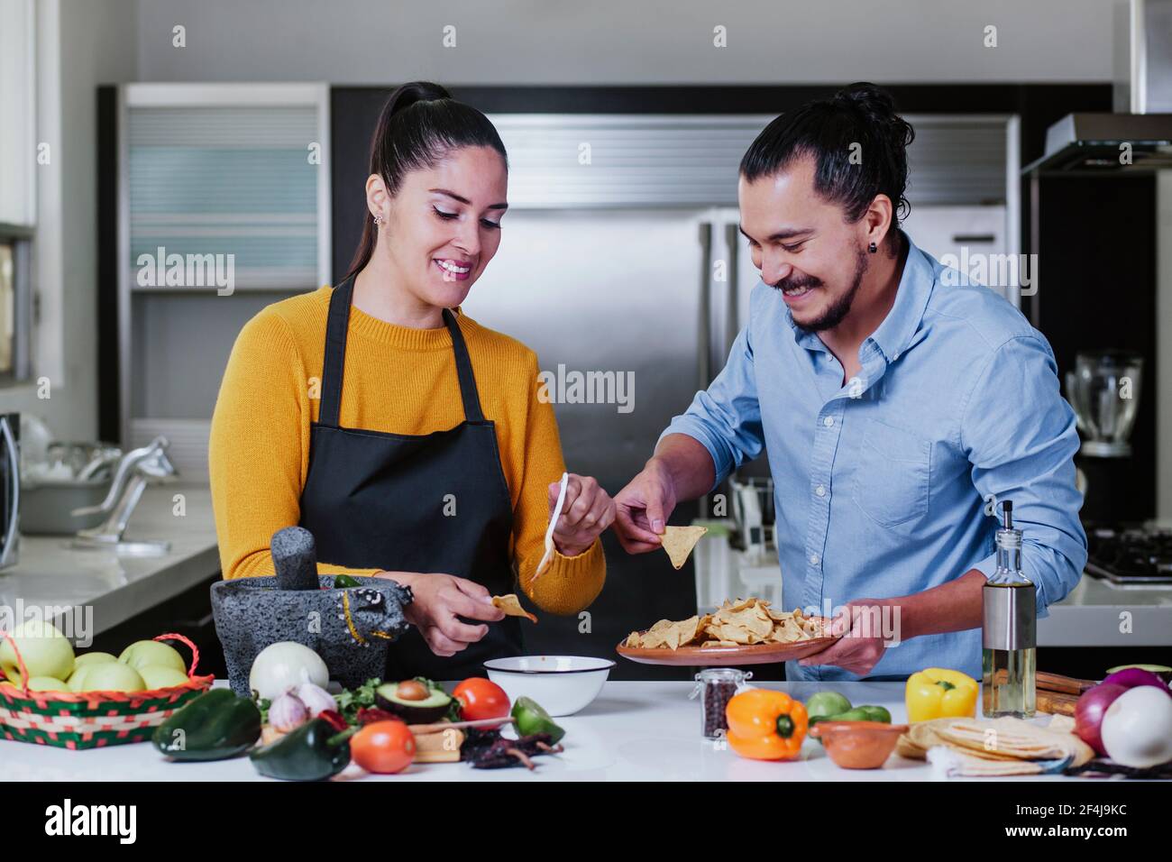 latin couple cooking mexican sauce together in their kitchen at home in ...
