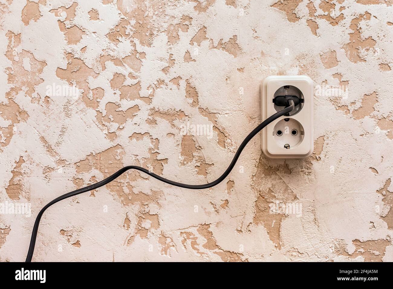 Black plug in a white double outlet on a white plaster background in a ...