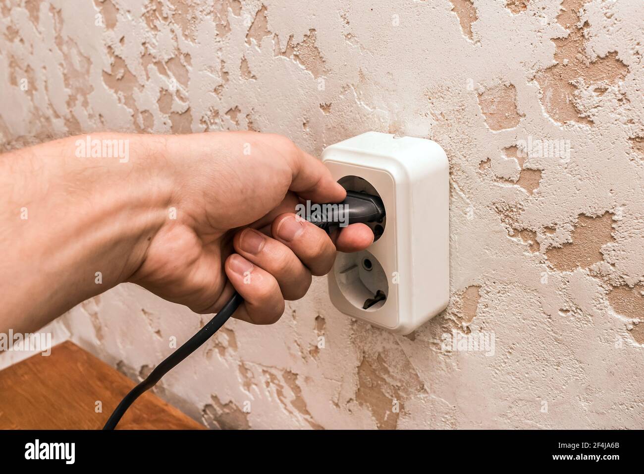 A man hand inserts or removes a plug from an outlet in a modern ...