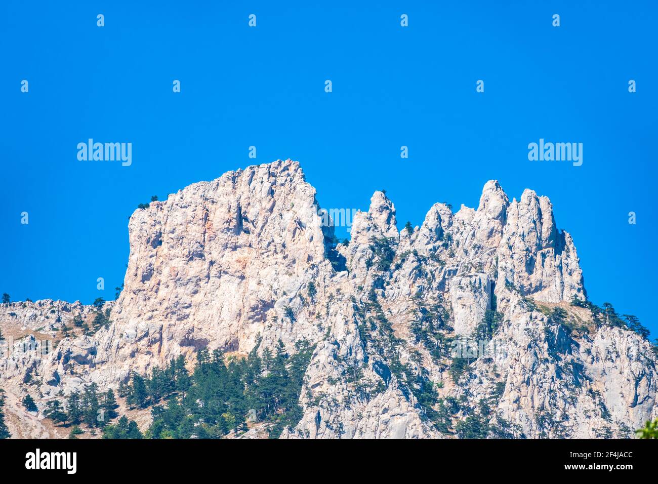 High mountains with forested slopes and peaks on blue sky background ...
