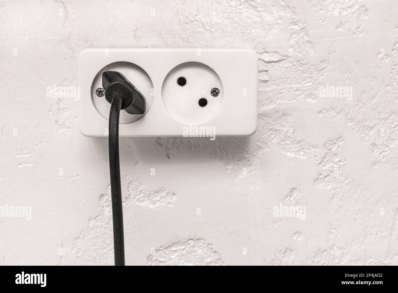 Black plug in white double socket on white plaster modern interior wall ...