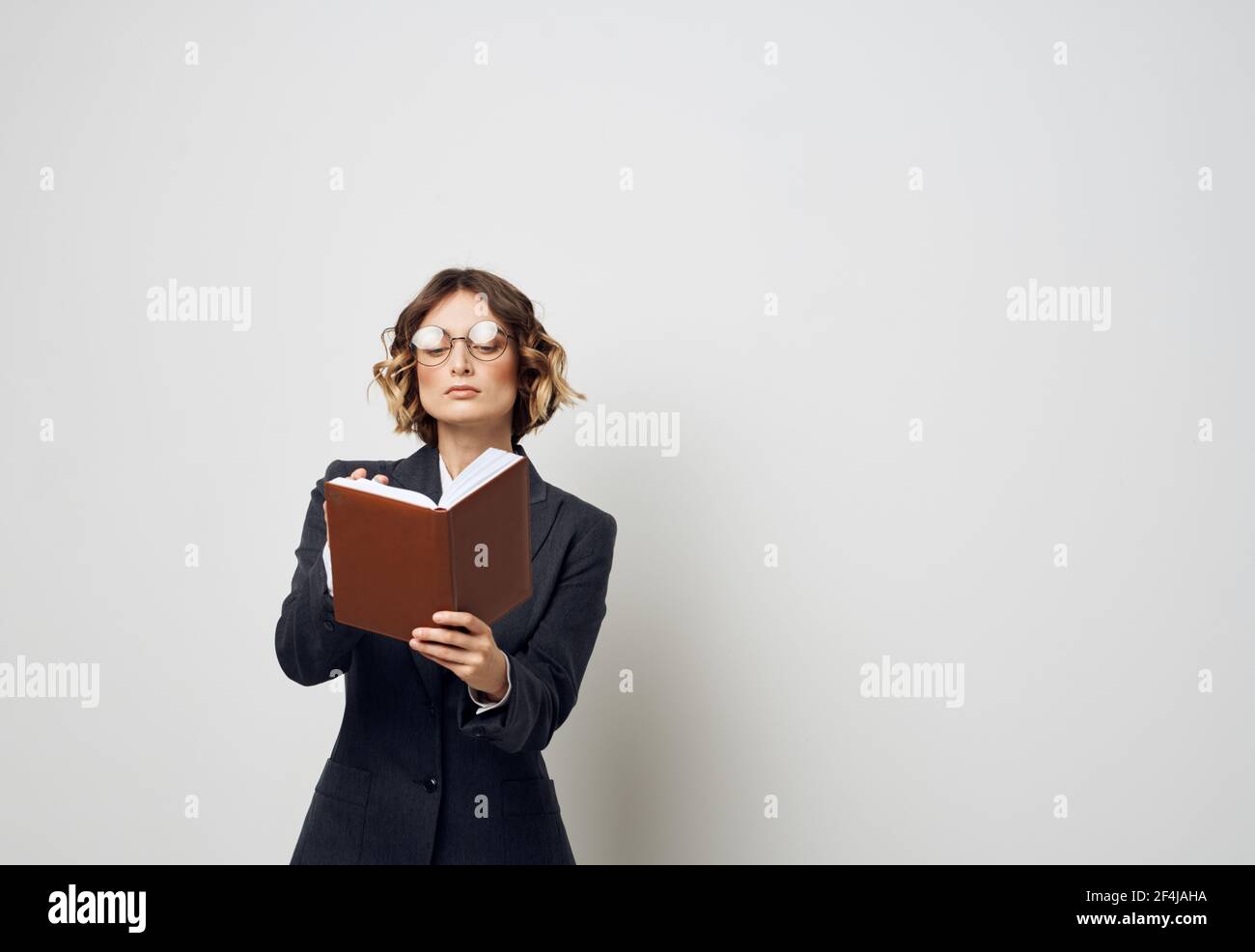 A woman in a suit with a notebook in her hands on a light background ...