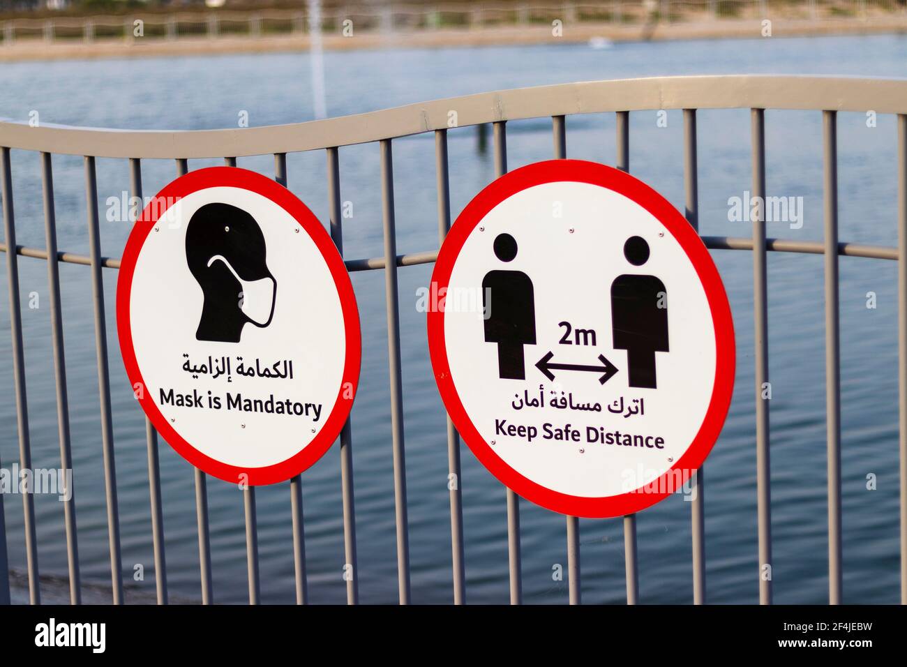 Covid 19 warning signs in Arabic and English languages on the fence of ...
