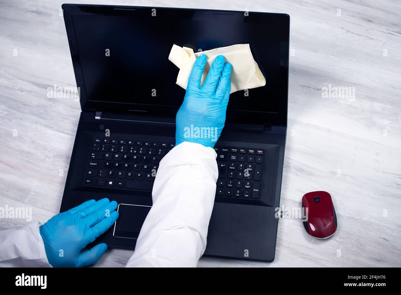 Office sanitizing wiping laptop with disinfectant. Coronavirus COVID-19 ...