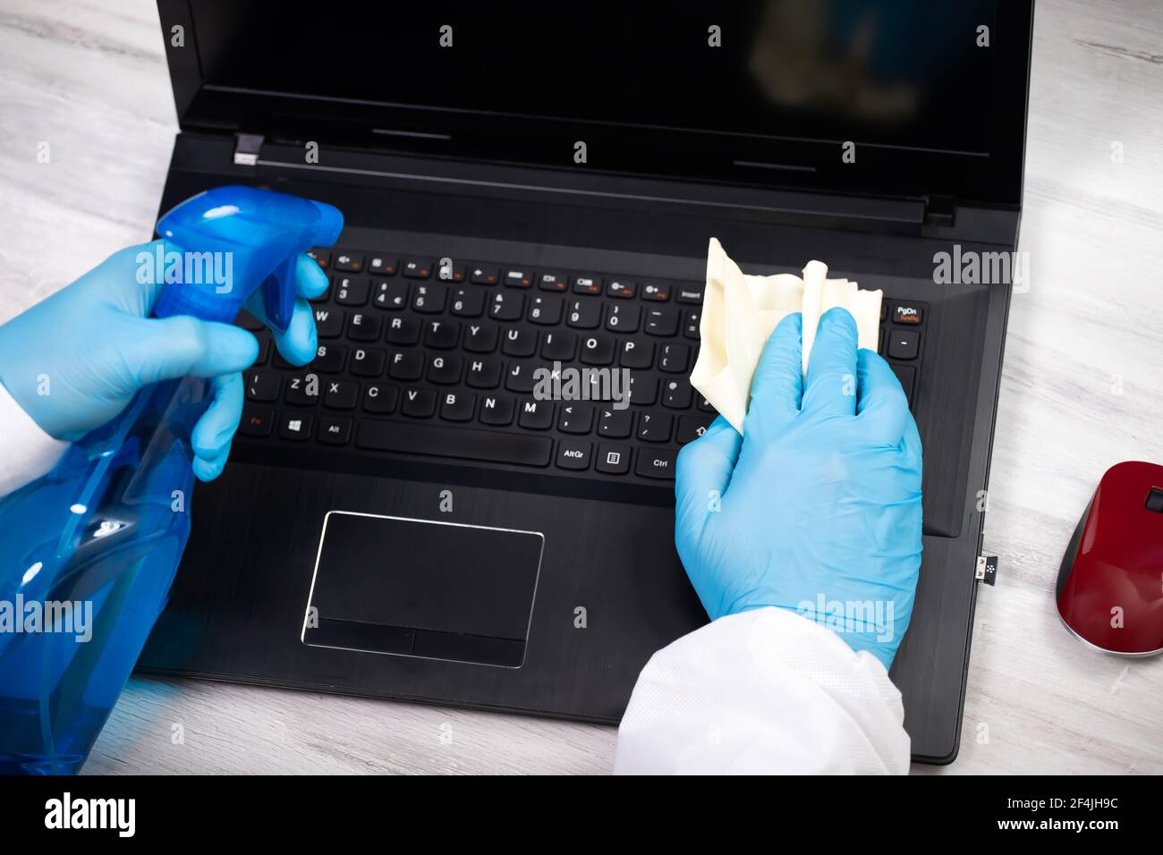 Office sanitizing wiping laptop with disinfectant. Coronavirus COVID-19 ...