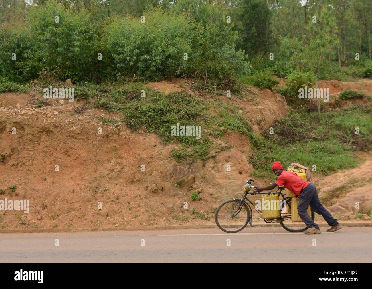 A Rwandan man pushing his loaded bicycle in rural Rwanda Stock Photo ...