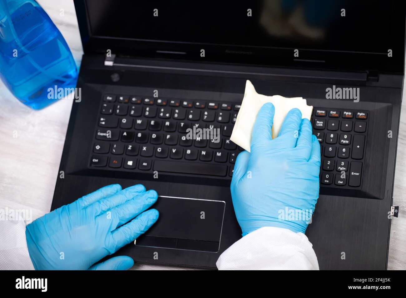 Office sanitizing wiping laptop with disinfectant. Coronavirus COVID-19 ...