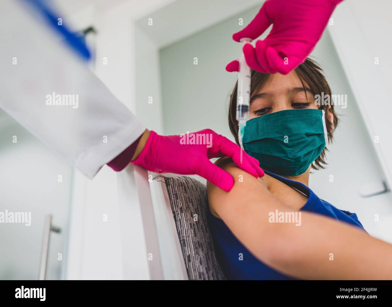 Little cute child with mask getting injection Stock Photo - Alamy