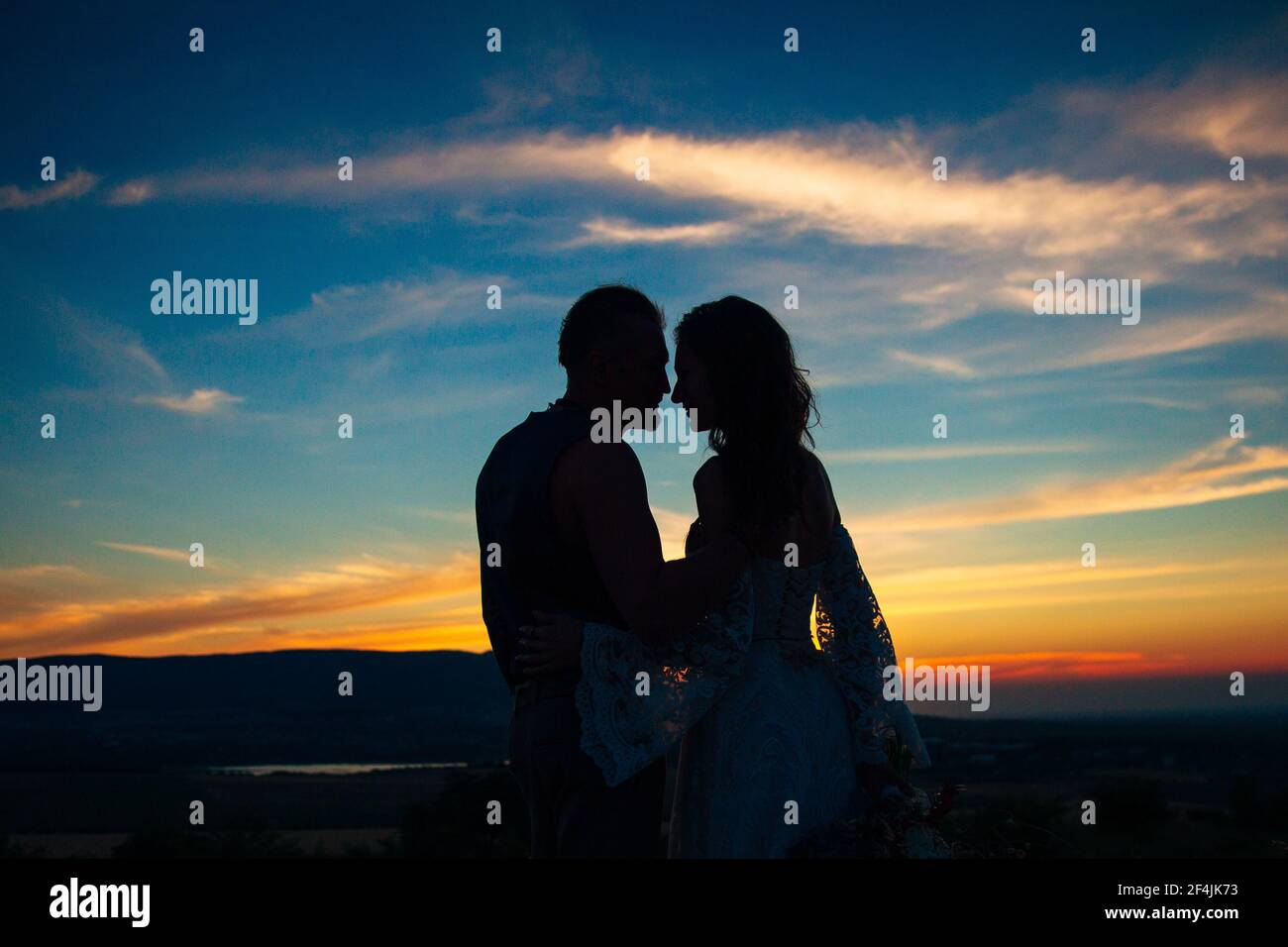 Silhouette of a couple hugging and kissing at sunset against the ...
