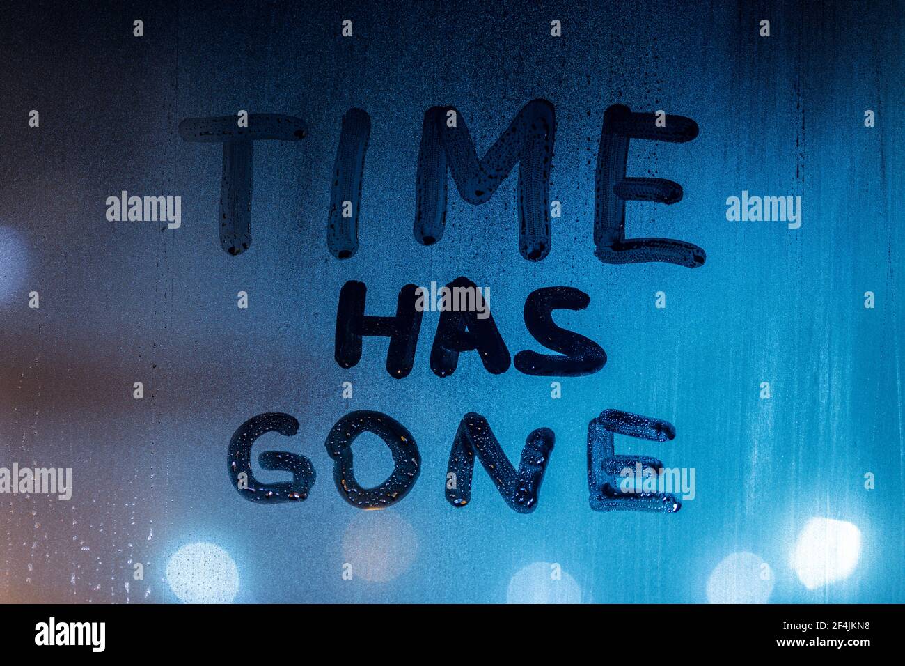 the words time has gone handwritten on night wet window glass surface ...