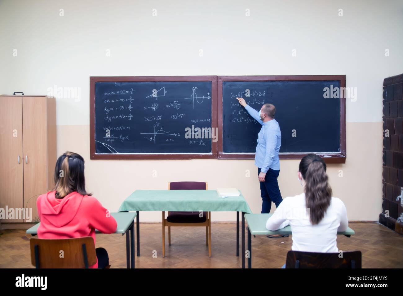 Teacher and his students wearing protective face mask in the classroom ...
