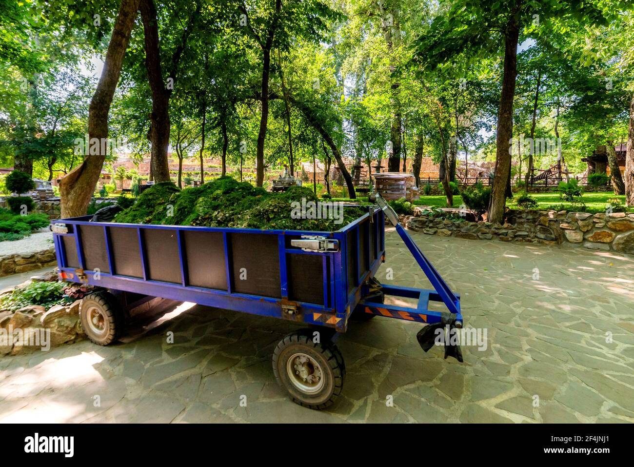 Blue modern trailer for a tractor with grass and ground in a botanical ...