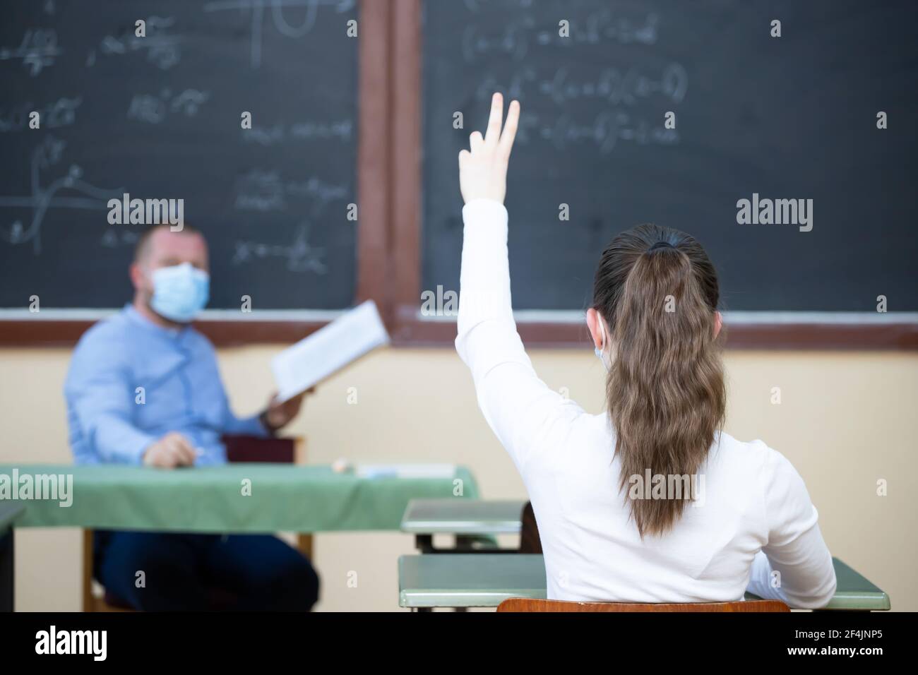 Teacher and his students wearing protective face mask in the classroom ...