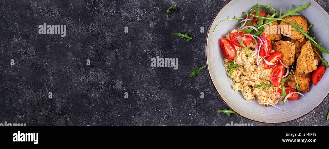 Boiled bulgur, roasted chicken nuggets and fresh tomatoes salad. Middle ...