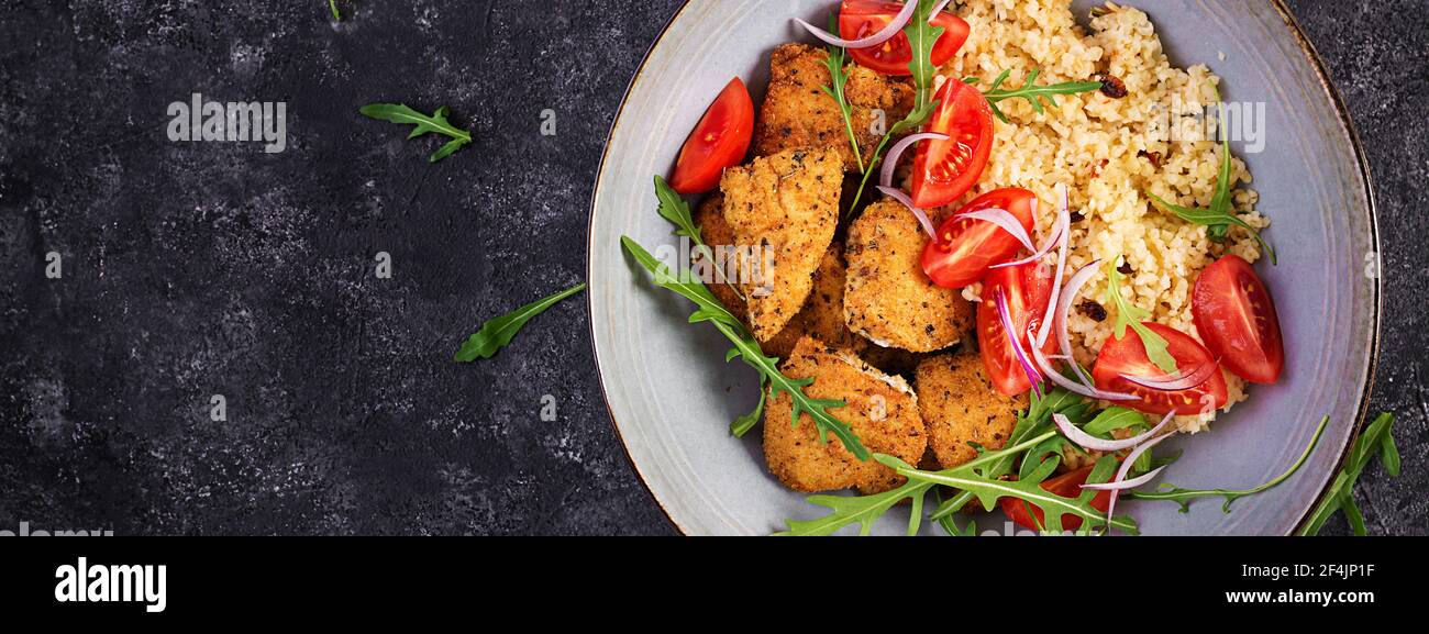 Boiled bulgur, roasted chicken nuggets and fresh tomatoes salad. Middle ...