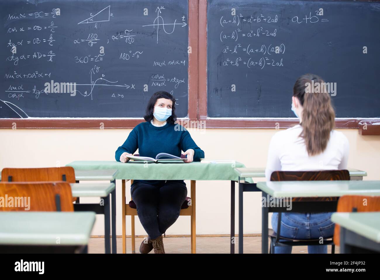 Teacher and her students wearing protective face mask in the classroom ...