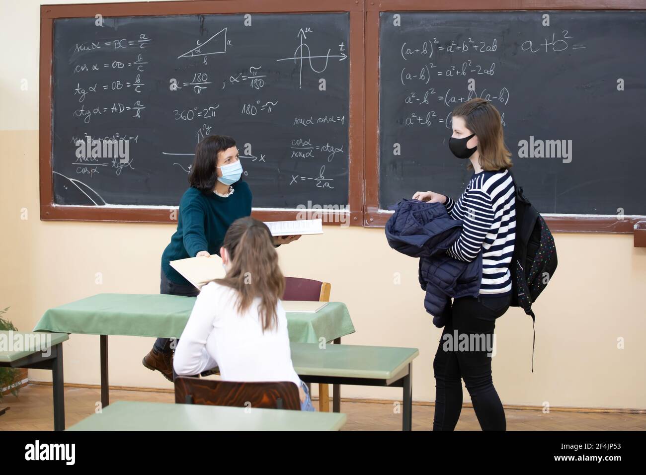 Teacher and her students wearing protective face mask in the classroom ...