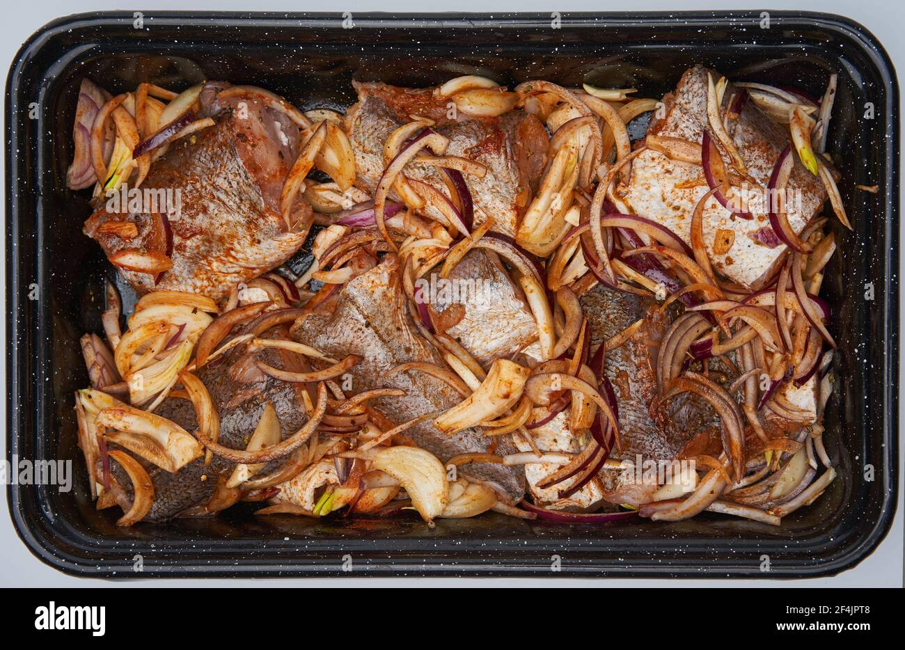 Seasoned fish ready to be cooked in a tray isolated on white background ...