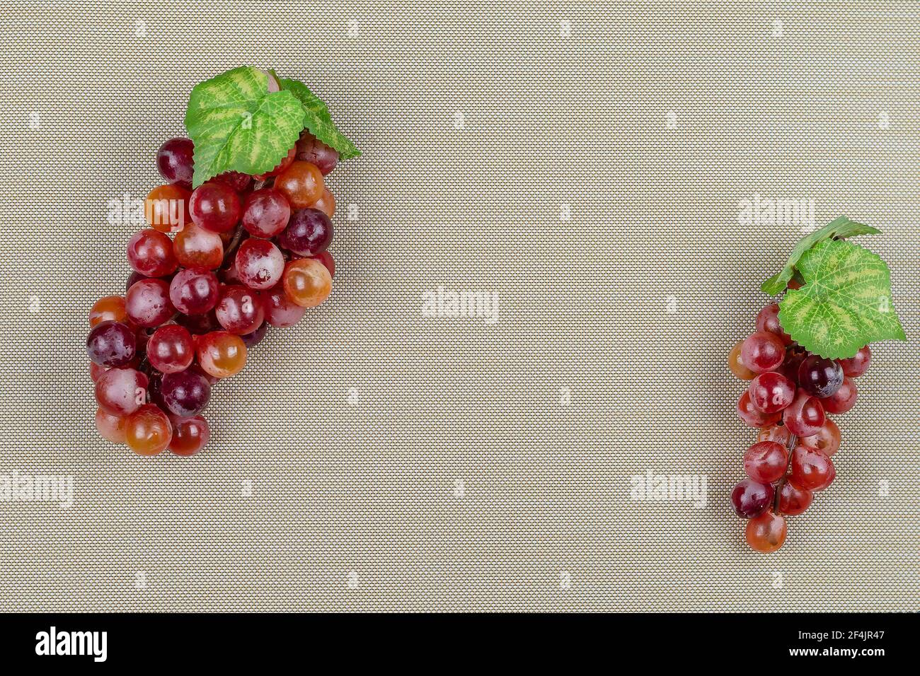 Two clusters of red grapes on a light brown background. Food ...