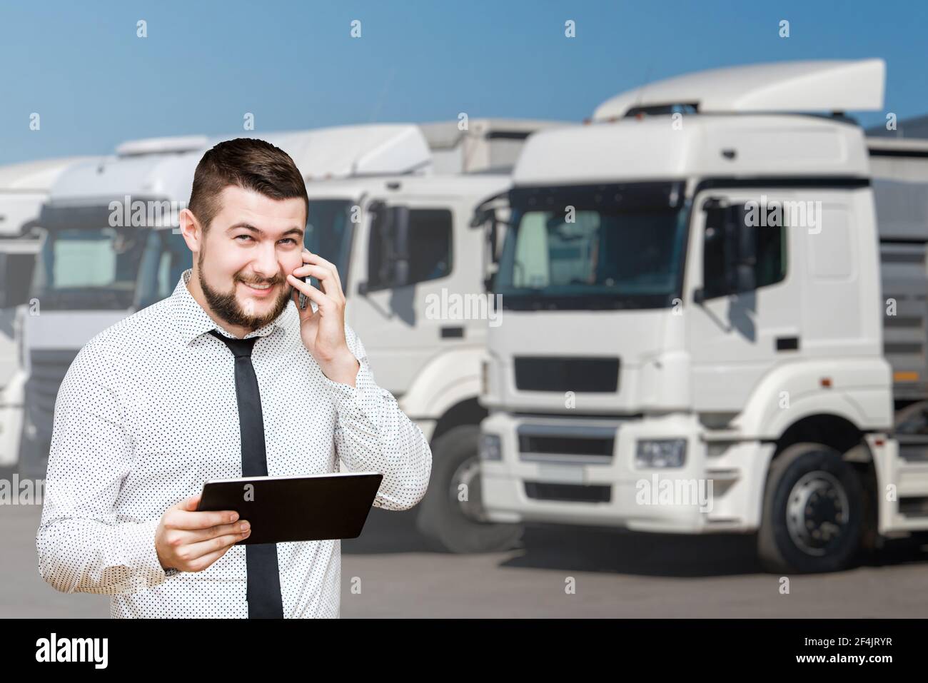 Manager with a digital tablet on the background of trucks. Fleet ...