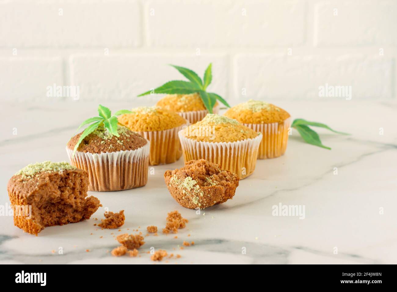 Marijuana cupcake muffins and cannabis leaves on a white marble table ...