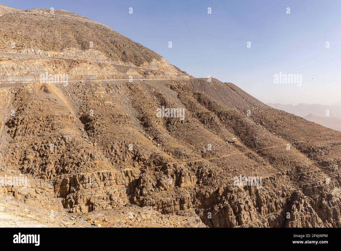 Jebel Jais mountain peak with winding tarmac road cutting the slope and ...