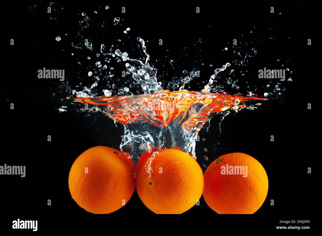Oranges falling into water against black background, studio shot Stock ...
