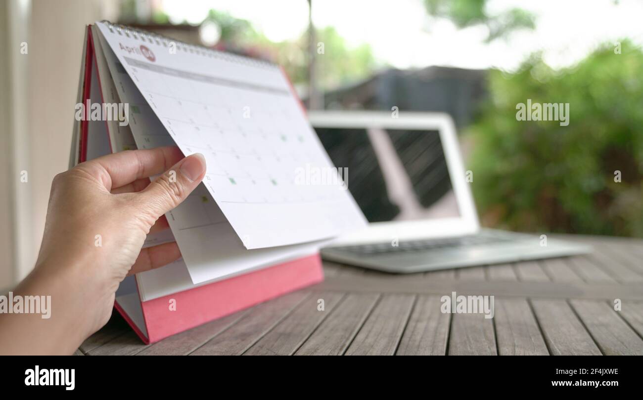 Hand on calendar with computer laptop at the background. Copy space ...