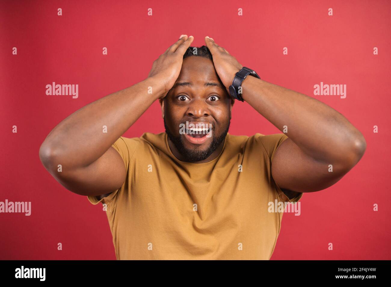 Scared and shocked African-American man holding head, looks at the ...