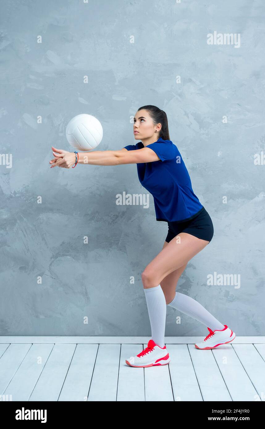 Volleyball girl hold and kick ball in blue costume on grey concrete ...