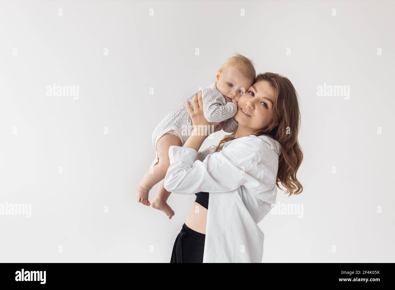 Young beautiful woman lift cute child in the air, smiling. Happy mother ...