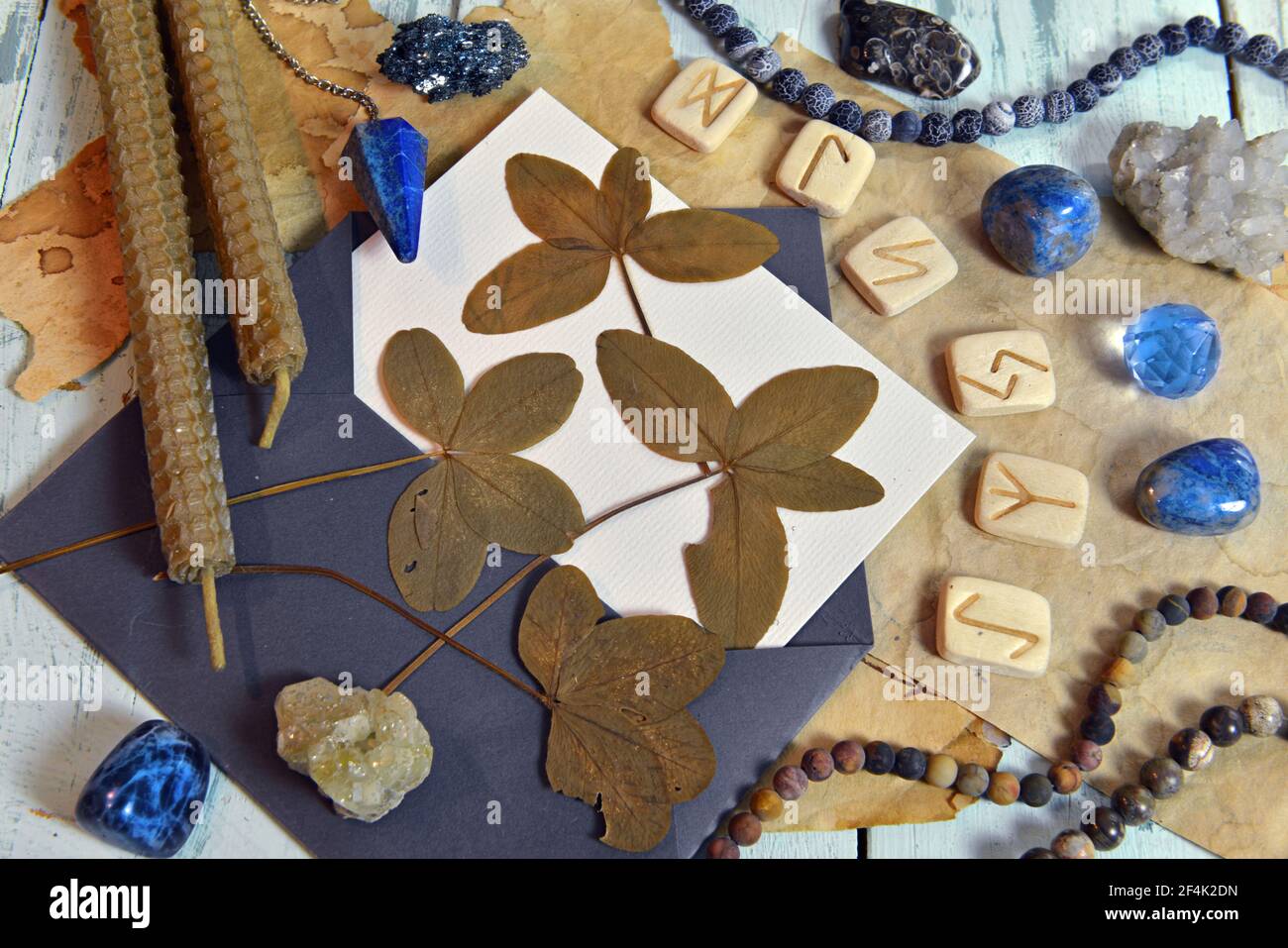 Still life with four leaf clover, runes, candles and crystals on witch ...