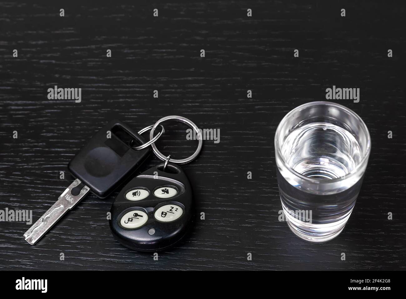 On the black table are the car keys and a shot of vodka close-up with ...