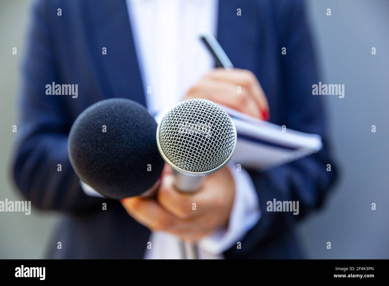 News reporter or TV journalist at press conference, holding microphone ...