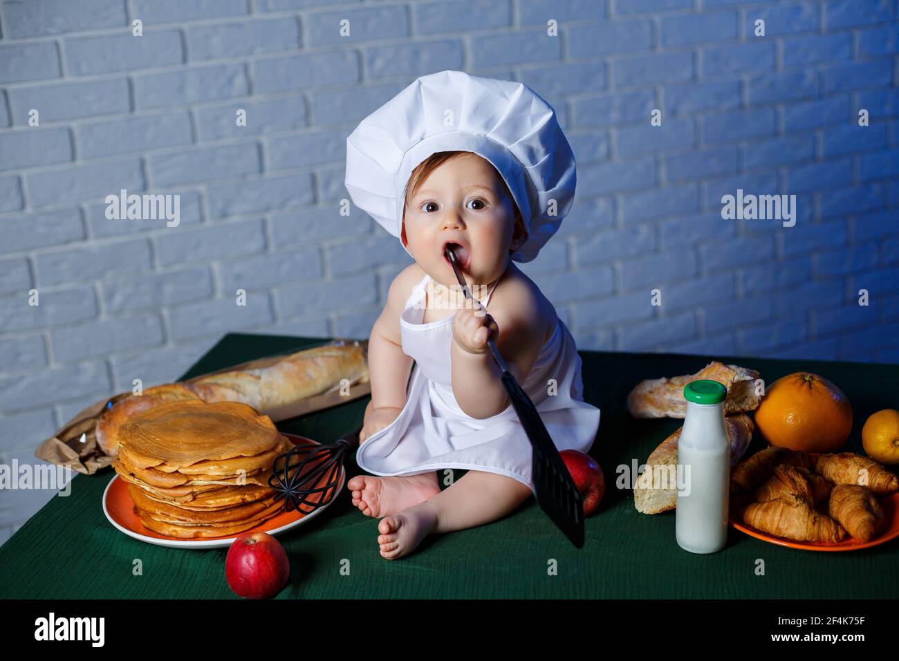 Little beautiful child dressed in an apron, children's cookery costume ...