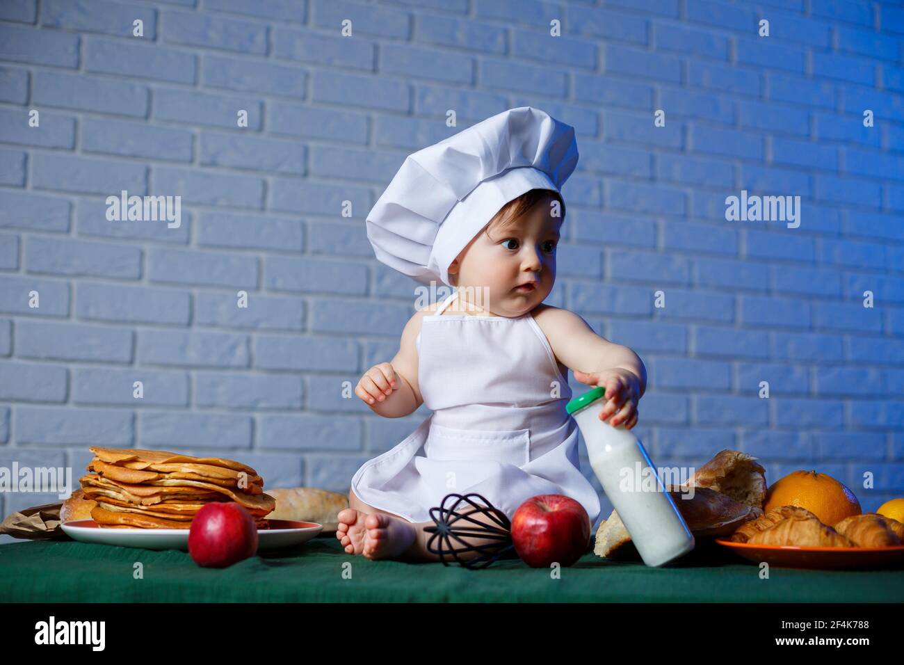 Little beautiful child dressed in an apron, children's cookery costume ...