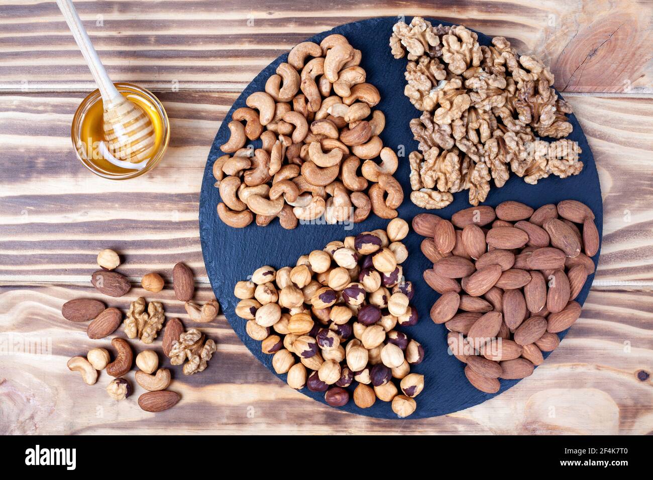 Various nuts sorted in glass bowl with honey bowl and honey dipper ...
