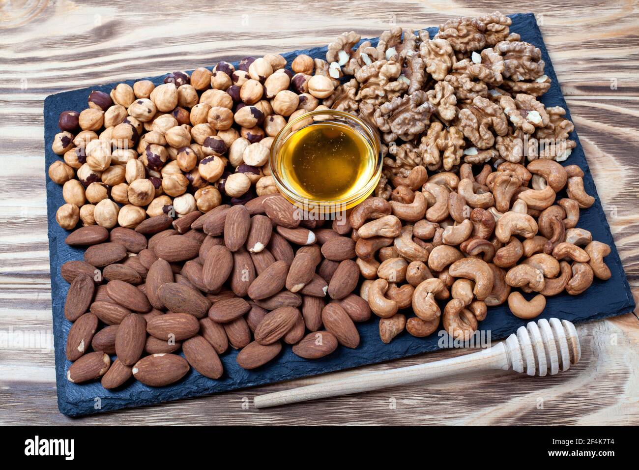 Various nuts sorted in glass bowl with honey bowl and honey dipper ...