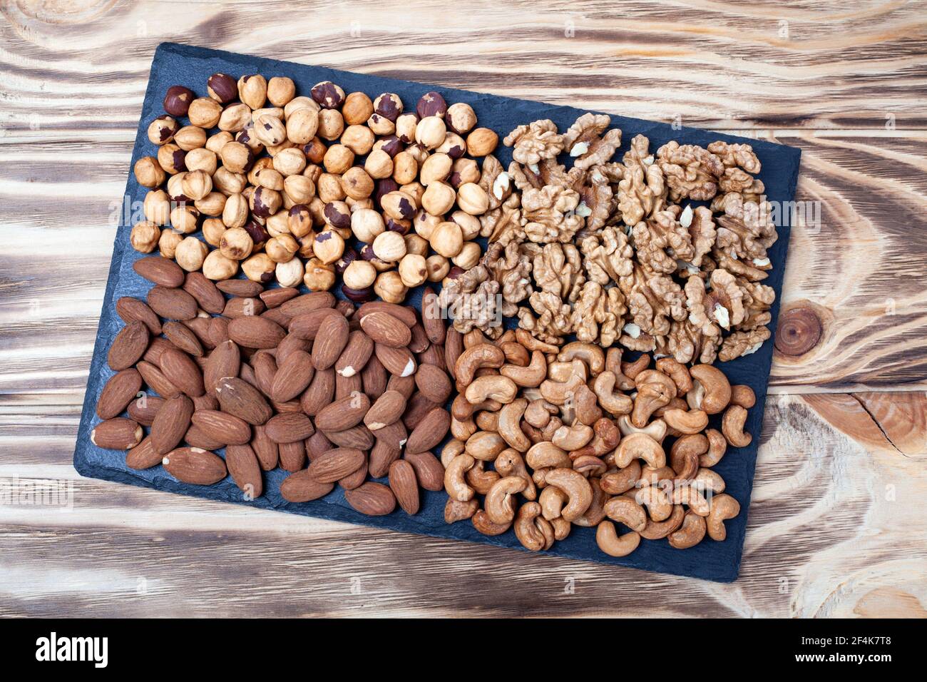 Various nuts sorted in glass bowl with honey bowl and honey dipper ...