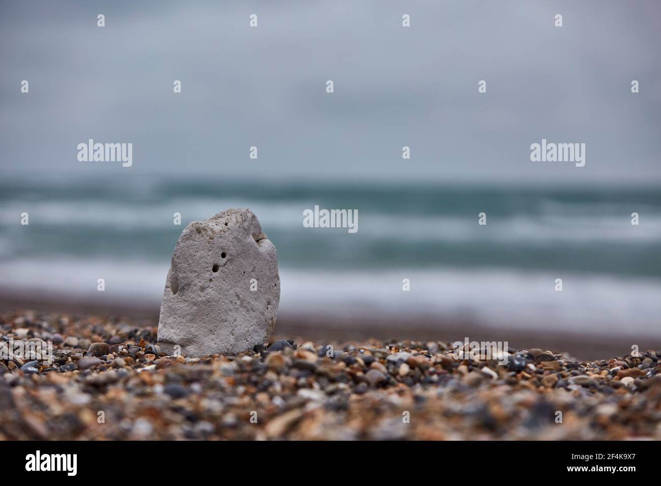 grey rock laying in the sand at the beach Stock Photo - Alamy
