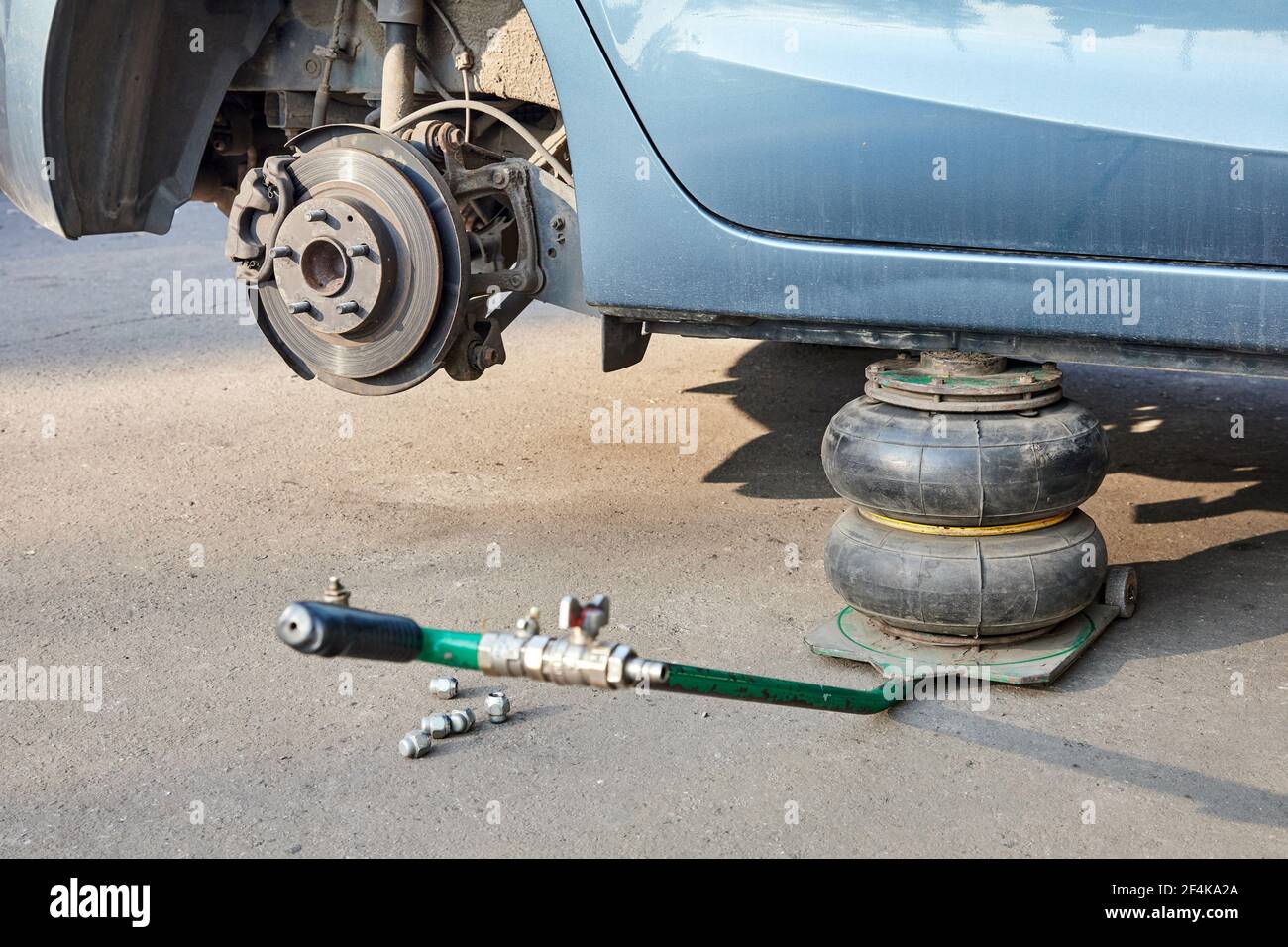 Car without wheels lifted up with jacks during wheel replacement ...