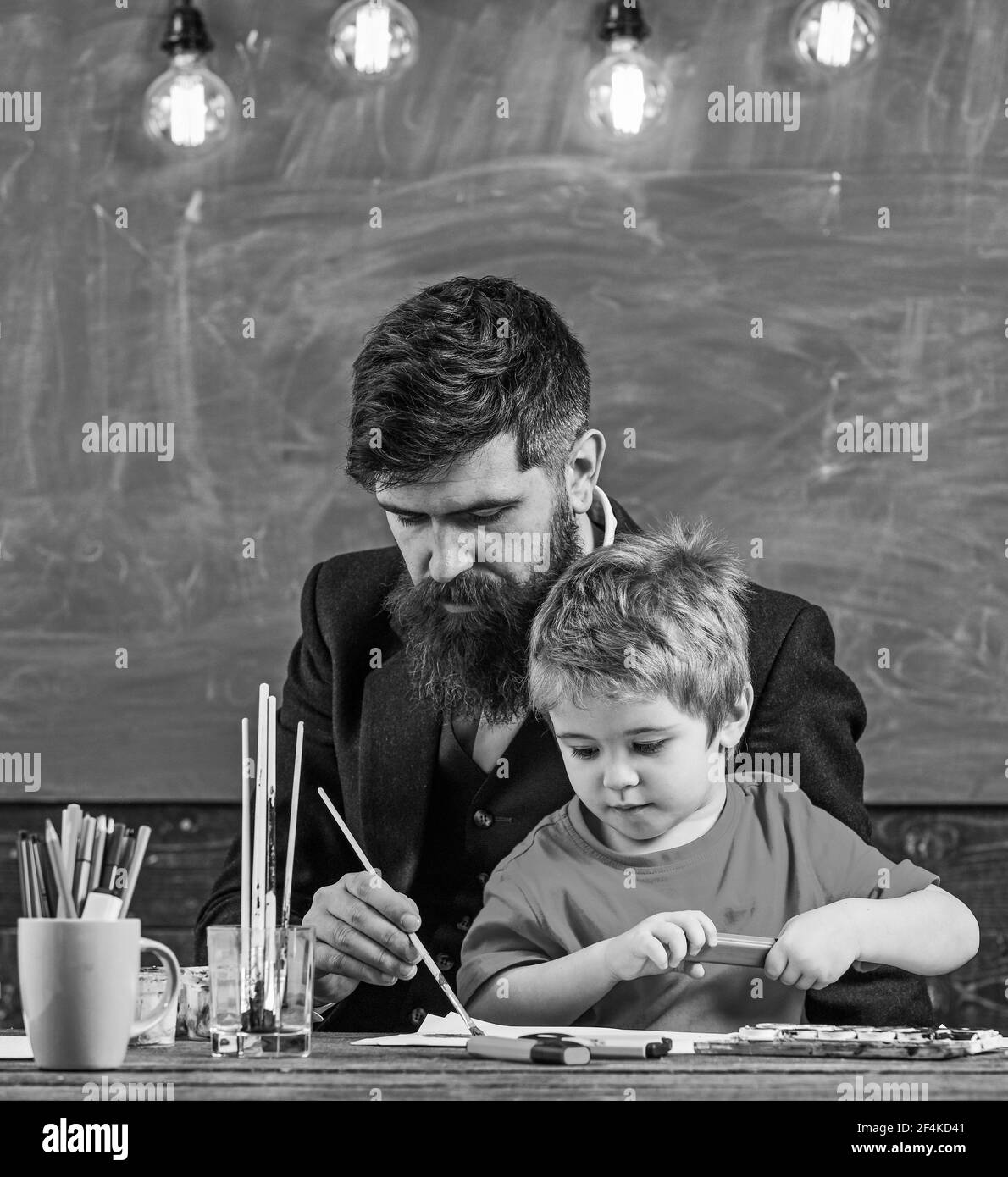 Daddy teaching his son how to paint. Cute kid watching his father ...