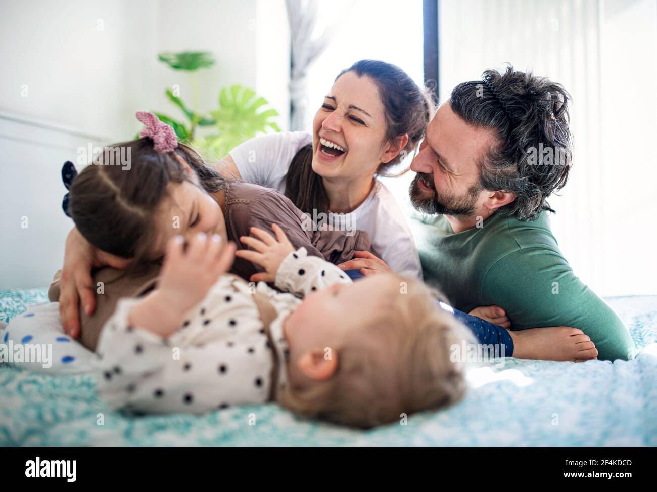 Family with two small daughters having fun on bed at home Stock Photo ...