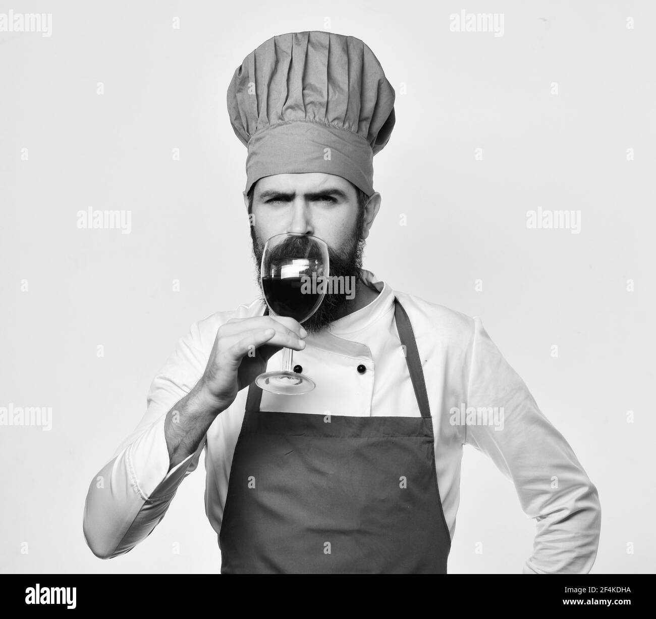 Cook with serious face in burgundy uniform drinks alcohol Stock Photo ...